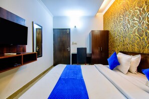 Quarto de hotel com cama, televisão na parede, guarda-roupa e papel de parede estampado.