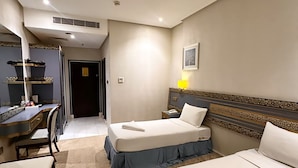 Quarto de hotel com duas camas, uma escrivaninha, uma cadeira e um espelho.