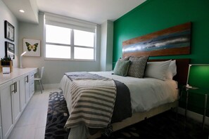 Quarto com cama, escrivaninha e janela.