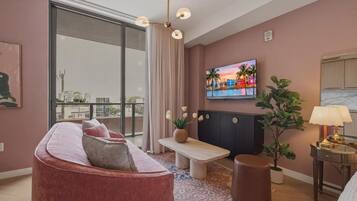 Uma sala de estar moderna com um sofá, um banquinho, uma TV e uma planta.