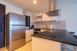 Cozinha moderna com geladeira de aço inoxidável, micro-ondas embutido e cafeteira.