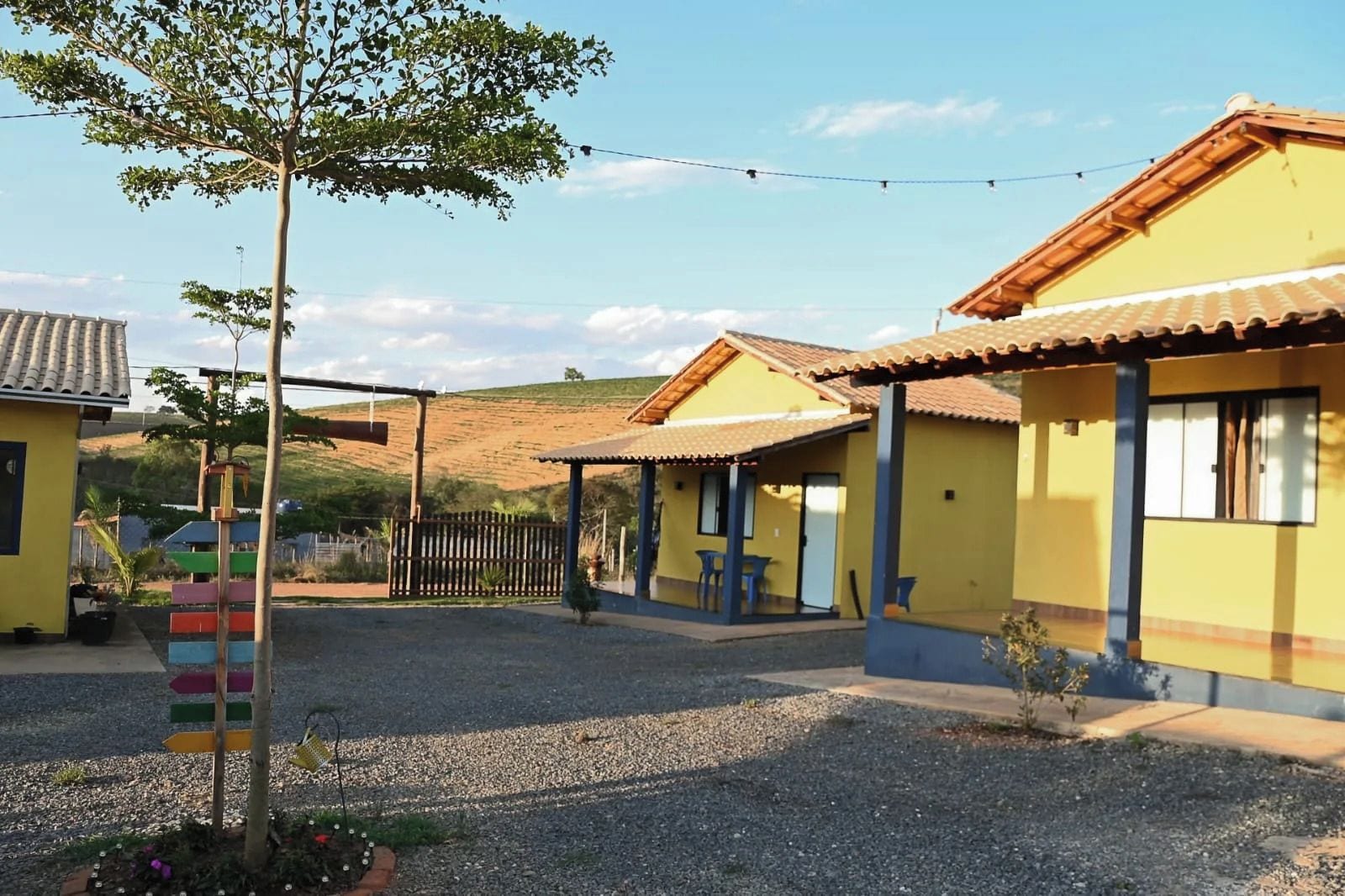 Bairro residencial com edifícios amarelos, uma árvore e entrada de automóvel com calçamento de brita.