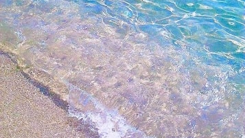 Uma praia com águas cristalinas e areal arenoso.