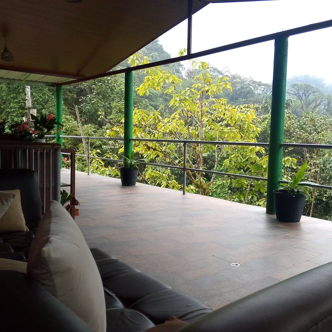 Área de estar coberta ao ar livre, com vista para vegetação exuberante.