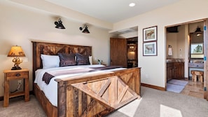 Quarto com cabeceira de madeira, mesa de cabeceira com abajur e cama com almofadas.