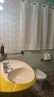 Casa de banho com lavatório amarelo, sanita branca e cortina de chuveiro.
