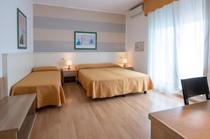 Quarto de hotel com duas camas de solteiro, uma escrivaninha e uma cadeira.