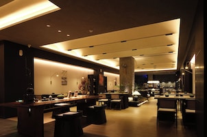 Um saguão de hotel moderno com balcão de recepção, área de estar e bar.