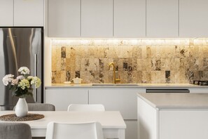 Uma cozinha moderna com painel de mármore, eletrodomésticos de aço inoxidável e área de jantar em branco.