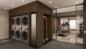 Uma lavanderia moderna com várias máquinas de lavar e secar, um espaço para engraxar sapatos e uma esteira, em ambiente comercial.