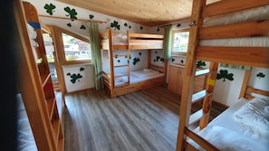 Quarto com beliches, piso de madeira e paredes decoradas com adesivos de trevo.