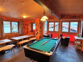 Uma mesa de bilhar em um ambiente com paredes de madeira e janelas.