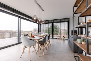 Uma sala de jantar moderna com uma mesa grande, cadeiras e iluminação pendente.
