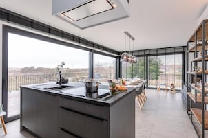 Cozinha moderna com uma ilha grande, área de jantar com vista e uma varanda espaçosa.