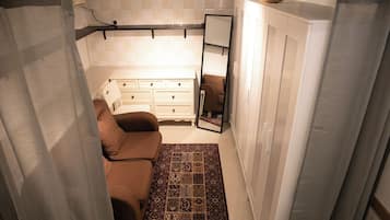 Casa de banho compacta com toucador branco, sofá castanho e tapete estampado.