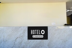 Balcão de recepção de hotel com placa indicando ser um hotel de serviço corporativo.