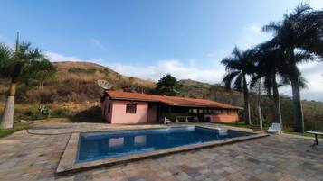 Uma casa com piscina, cercada por palmeiras e uma paisagem montanhosa.