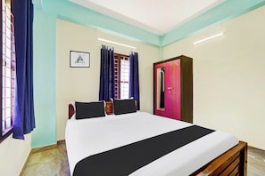 Quarto de hotel com cama, guarda-roupa, janela com cortinas e um quadro na parede.