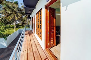 Corredor com portas e janelas de madeira, parede branca e chão de madeira.