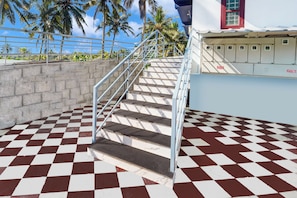 Escadaria com piso xadrez que leva a um edifício com janela vermelha e fileira de armários.