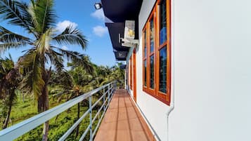 Um corredor com guarda-corpo, palmeiras e um edifício com grandes janelas.