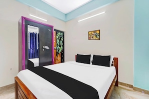 Quarto com cama, porta com cortina, quadro na parede e luz no teto.