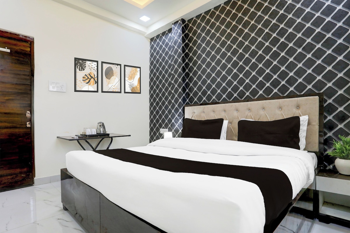 Quarto moderno com cama, mesa de cabeceira, prateleira na parede e painel decorativo.