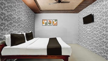 Quarto com uma cama, um ventilador de teto e três obras de arte emolduradas na parede.