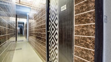 Um corredor com porta estampada, placa de número e chão de azulejos.