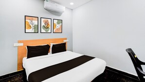 Quarto de hotel com cama, cabeceira, ar condicionado fixado na parede e três obras de arte emolduradas.