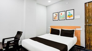Quarto de hotel com uma cama, uma cadeira e três obras de arte emolduradas na parede.