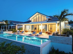 Uma casa moderna com piscina, área de estar externa e interior bem iluminado.