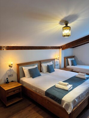 Quarto de hotel com uma cama grande, mesas de cabeceira, abajur e luminária no teto.
