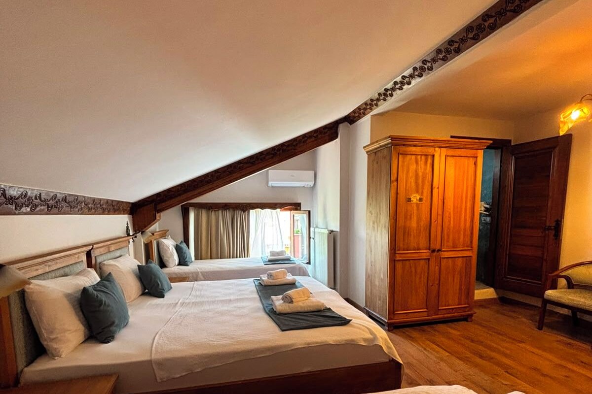 Quarto de hotel com duas camas, um guarda-roupa e vista para o exterior.