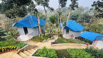 Um declive com duas pequenas construções de telhado azul, cada uma com uma escadaria até a porta.