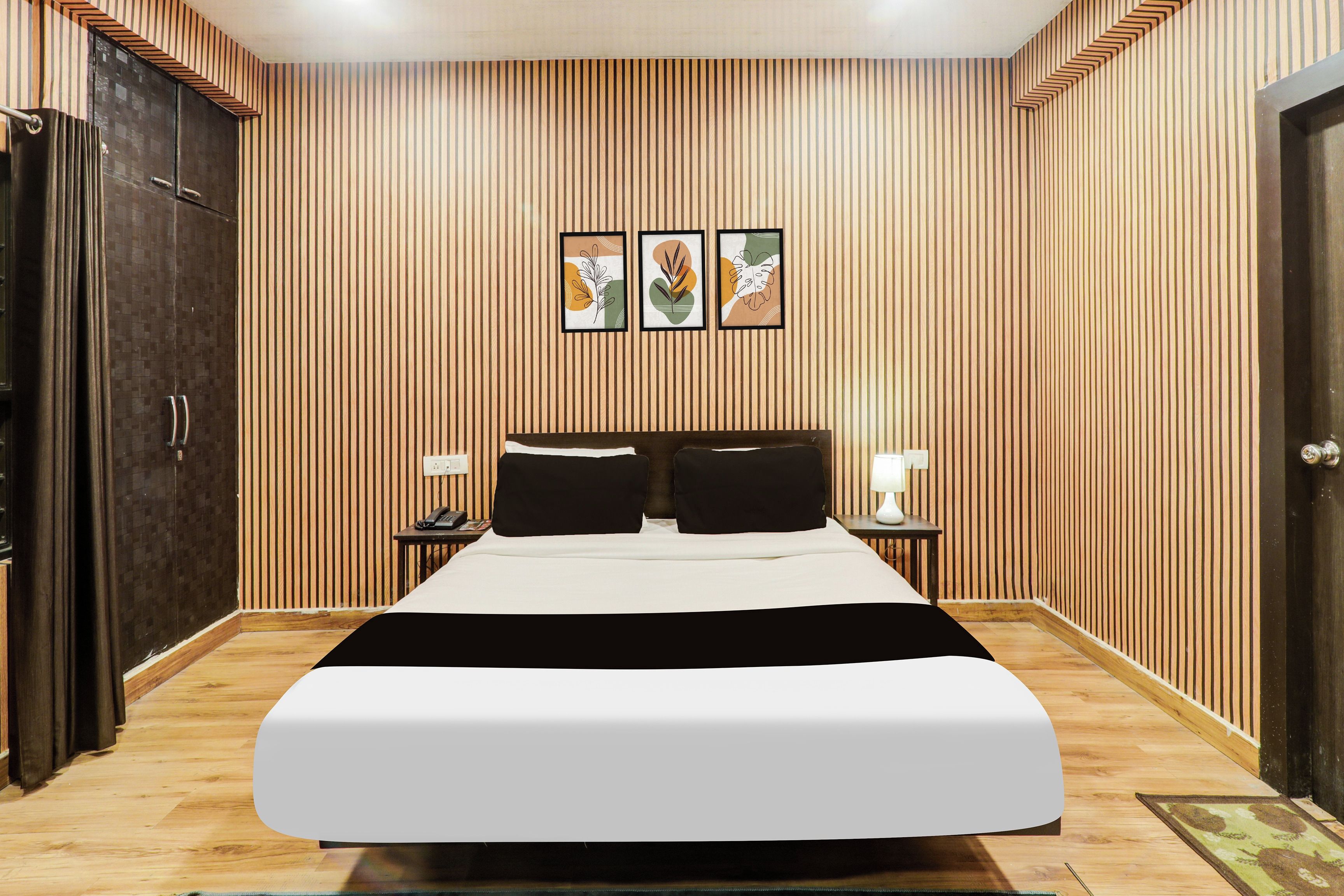 Quarto de hotel com uma cama grande, parede de ripas de madeira e porta à esquerda.