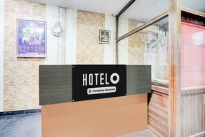 Balcão de recepção de hotel com aviso indicando serviço da empresa.