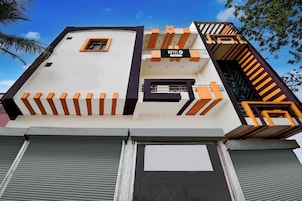 Um hotel moderno com fachada branca, detalhes em laranja e uma placa indicando ser um hotel de serviço corporativo.