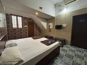 Quarto com cama, mesinha, um banco, janela e porta.