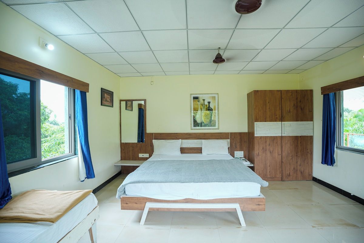 Quarto com cama, guarda-roupa, mesa de cabeceira e janela com cortinas.