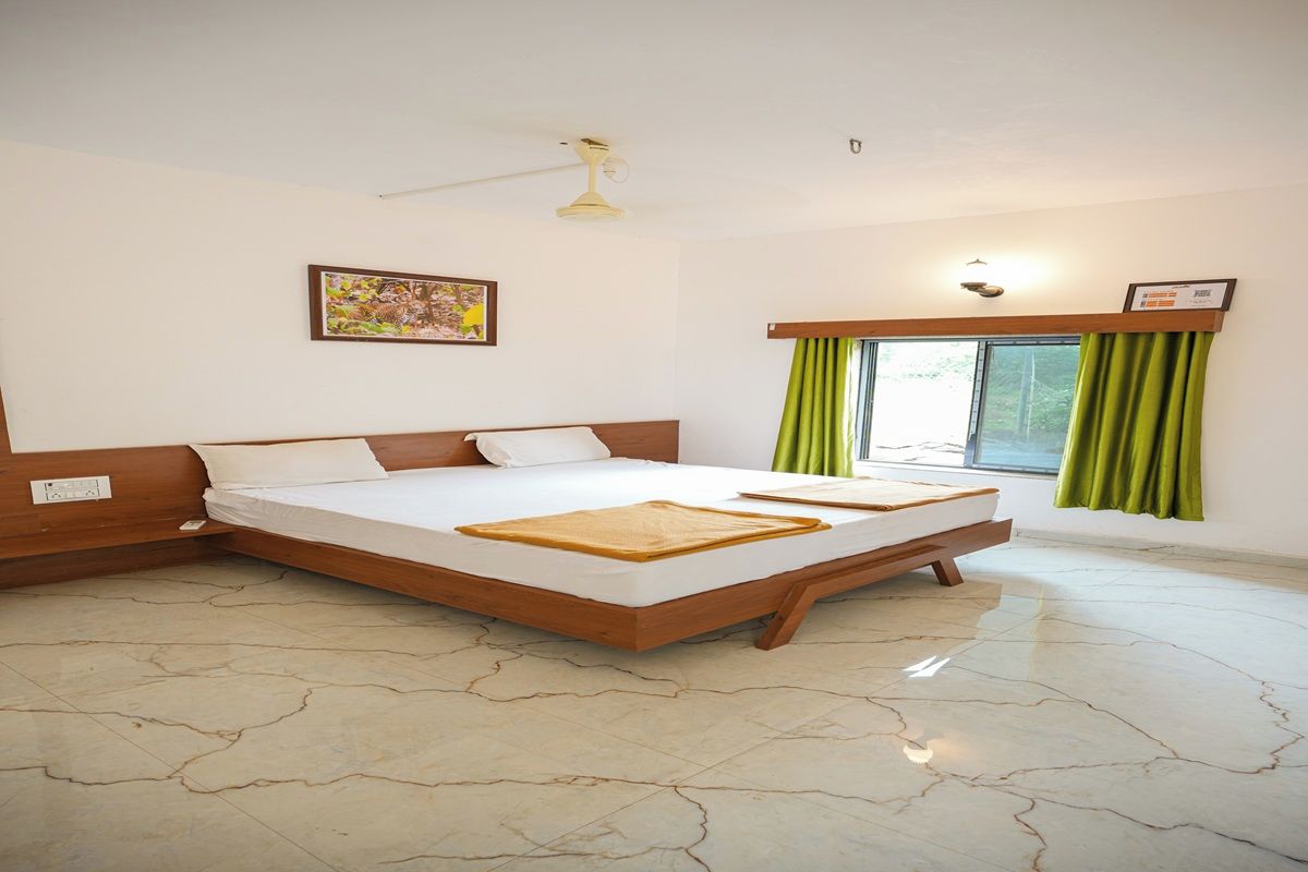 Quarto com cama, ventilador de teto, janela com cortinas e luminária fixada na parede.