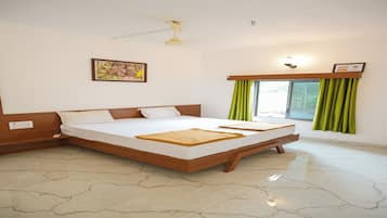 Quarto com cama, ventilador de teto, janela com cortinas e luminária fixada na parede.
