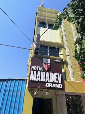 Placa de hotel com o nome 'Hotel Mahadev Grand' e um logotipo.