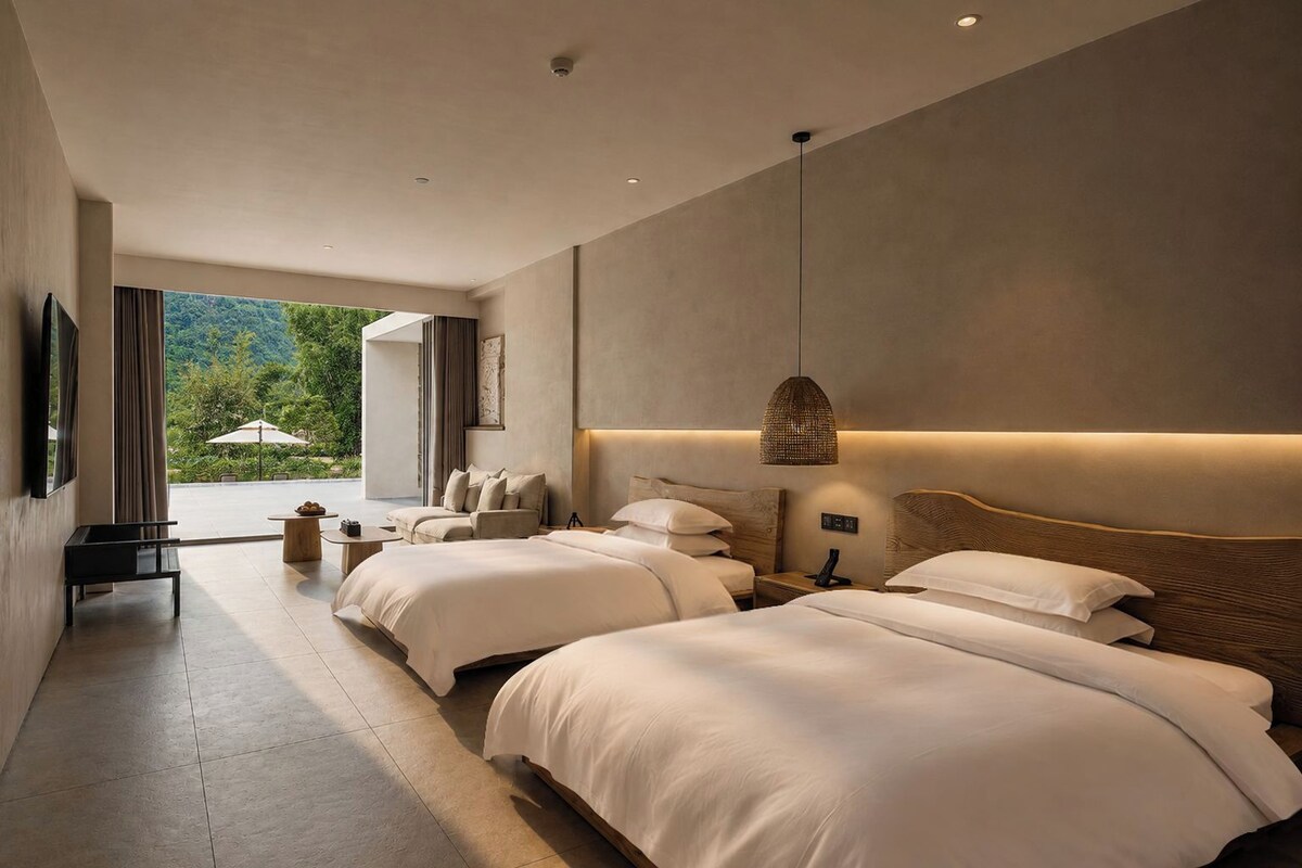 Quarto moderno com duas camas, uma janela ampla e vista para o verde.