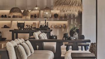 Um interior moderno com um sofá, uma mesa com objetos decorativos e luminárias pendentes.