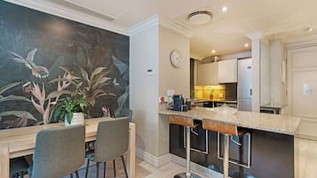 Uma cozinha moderna com bancada, mesa de jantar com cadeiras e um grande mural na parede.
