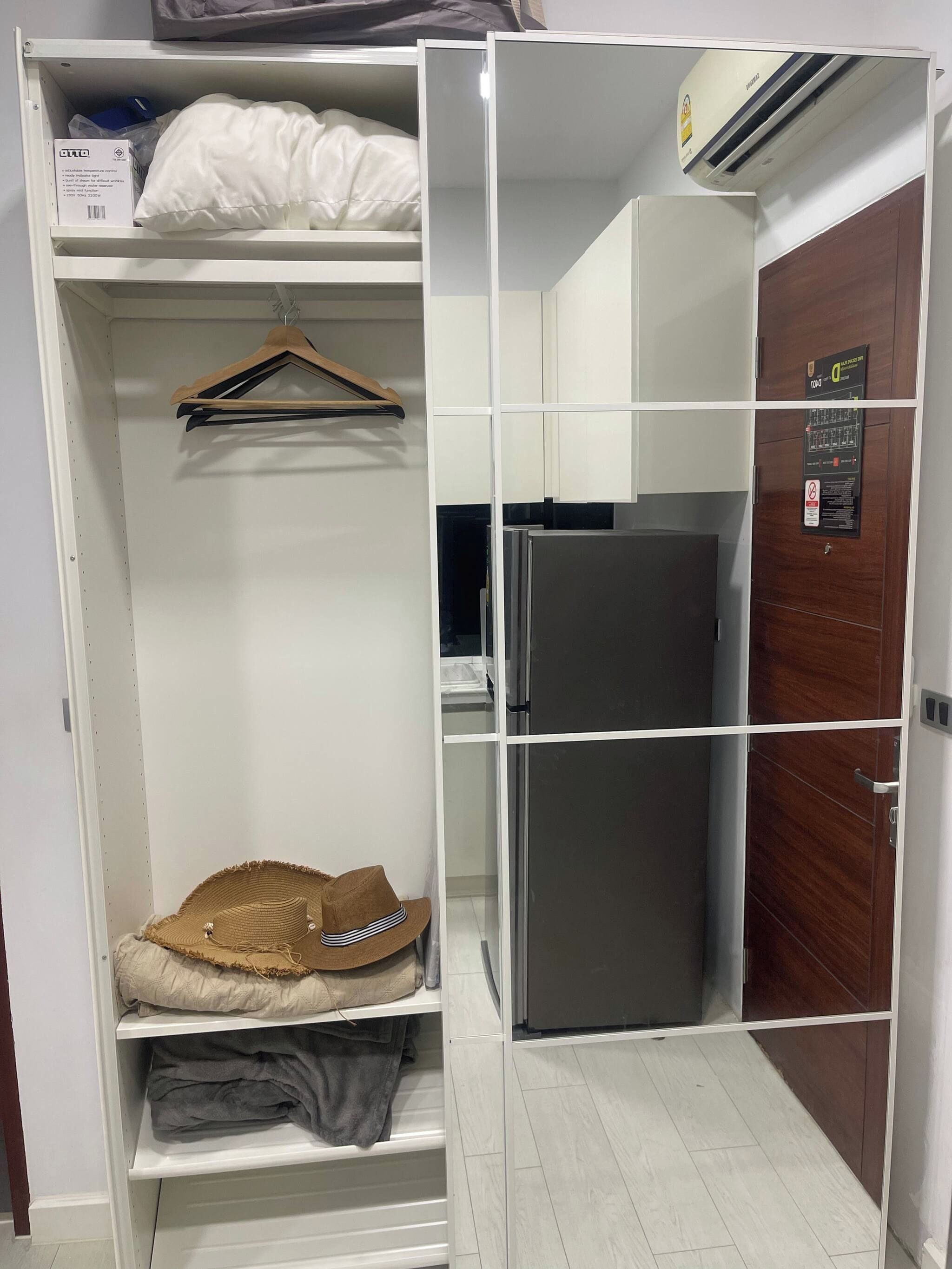 Um closet espaçoso com cabideiro, chapéu dobrado e uma geladeira.