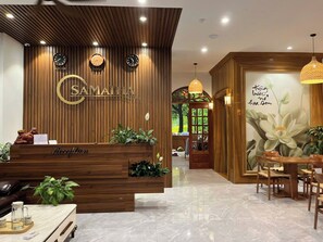 Bancada de recepção com acabamento em madeira, um relógio e uma placa com a inscrição 'SAMHA Hotel'.