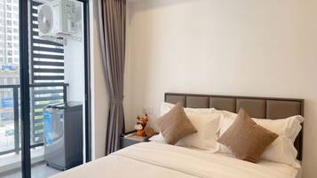 Quarto de hotel com uma cama, mesa de cabeceira, um vaso decorativo e vista para a cidade pela janela.