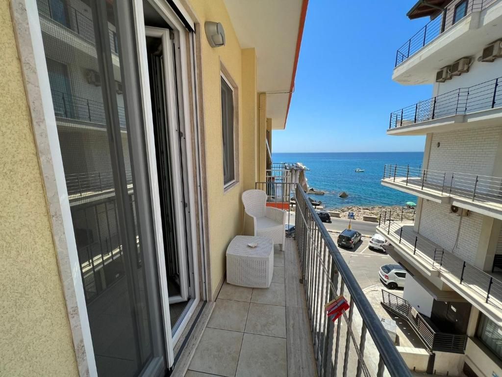 Uma varanda com vista para o mar, uma cadeira branca e uma pequena mesa.